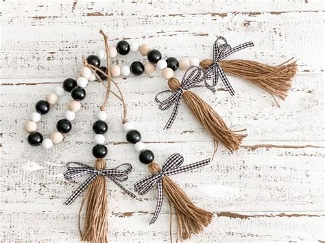 Three Tassels With Black And White Beads Are Arranged In The Shape Of A