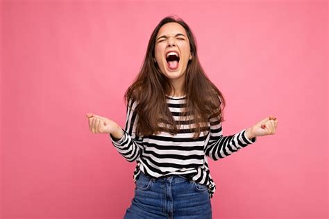 자유로운 공간과 함께 핑크 배경에 고립 된 캐주얼 스트라이프 풀오버에 진심 어린 감정을 가진 젊은 감정적 긍정적 인 매력적인