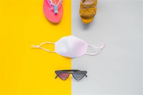 플립 플롭 선글라스 하이힐 샌들 노란색과 회색 판지의 마스크 반으로 나누어 배경에 깔끔하게 다른 신발여름과 코로나 바이러스 개념