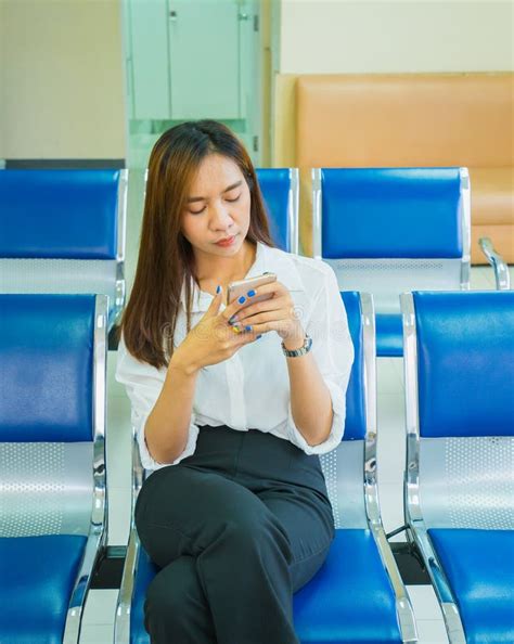 Women Using Mobile While Waiting For Queue In Hospital Stock Image