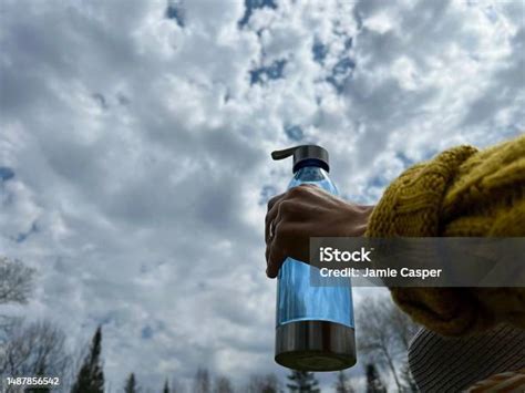 리필 가능한 물병을 하늘에 들고 있는 여성의 손의 부분적인 모습 45 49세에 대한 스톡 사진 및 기타 이미지 45 49세 건강한 생활방식 경관 Istock