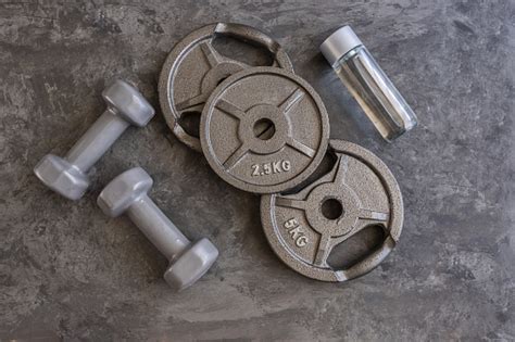 체육관에서 시멘트 바닥에 바벨 아령과 물 병에 대한 무게 플레이트 웨이트 트레이닝 및 건물 근육을위한 장비 스포츠 또는 운동을 위한 개념 개념에 대한 스톡 사진 및 기타