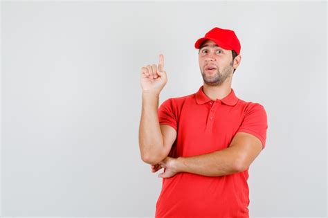 Free Photo Delivery Man In Red T Shirt Cap Pointing Finger Up