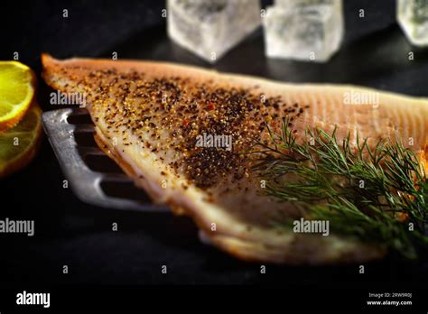 A Trout Fillet Is Garnished With Lemon Ice Cube Cubes And Dill On A