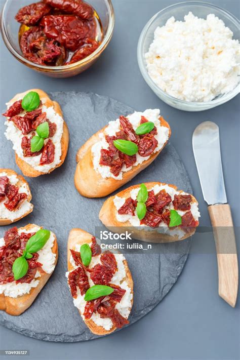 태양 말린 토마토 페타와 필라델피아 치즈와 바 질 온 돌 판 수직 탑 뷰 근접 촬영의 브루스 케 타 건강한 식생활에 대한 스톡