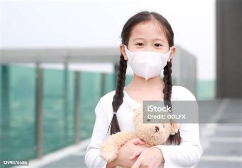 클로즈업 아시아 의 어린 소녀 포옹 테디 베어 인형에 마스크를 착용 코로나 바이러스와 방콕 도시에서 대기 오염에 대 한 태국