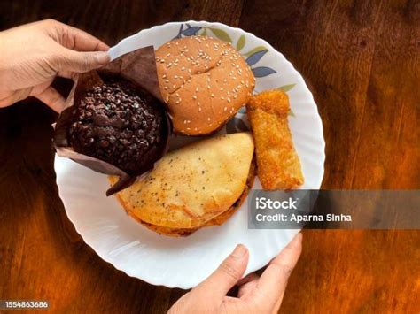 접시에 다양한 스낵이 전시되어 있고 한 손이 나무 배경에 초콜릿 머핀을 들고 있다 0명에 대한 스톡 사진 및 기타 이미지 0
