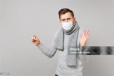 스웨터 스카프 무 균 얼굴 마스크 홀드 온도계 회색 배경에 고립 손을 확산 충격 젊은 남자 건강 한 라이프 스타일 아픈 질병 치료 추운 계절 개념입니다 복사 공간을 모의