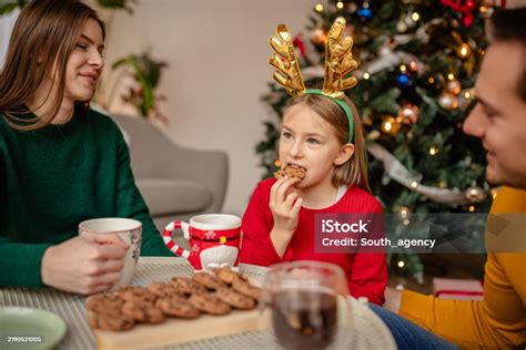 겨울 축제 시즌에 나무 근처에서 함께 크리스마스 쿠키를 즐기는 가족 3 명에 대한 스톡 사진 및 기타 이미지 3 명 가정 생활 가정용 건축물 Istock