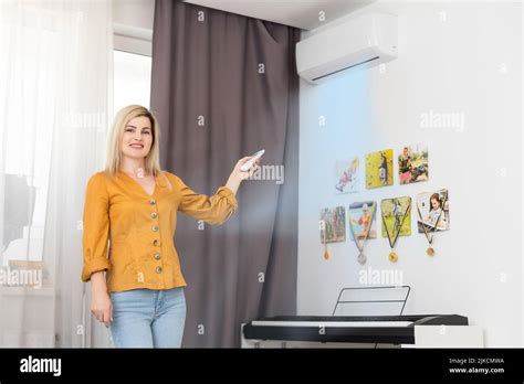 Air Conditioner Inside The Room With Woman Operating Remote Controller Air Conditioner With