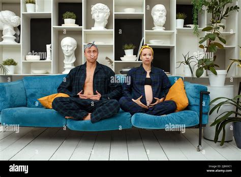 A Pregnant Man And Woman Are Meditating In A Lotus Position On The