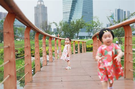 도시 공원의 물 연못 위에 지어진 붉은 보도에서 놀고있는 두 명의 중국 여성 어린이 2 3 살에 대한 스톡 사진 및 기타 이미지