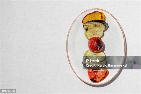 구운 야채 구운 파프리카 가지 토마토 호박 음식은 가벼운 식탁보에 가벼운 세라믹 접시 위에 놓여 있습니다 가지 채소에 대한 스톡