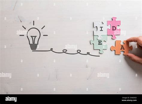 Male Hand Assembling Four Colorful Matching Puzzle Pieces To Spell The Word Idea Connected To A