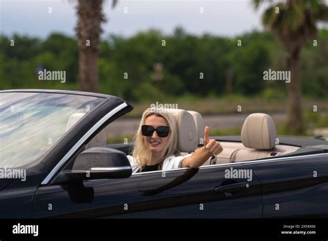 Close Up Of A Young Smiling Blonde Woman In Sunglasses At The Wheel Of