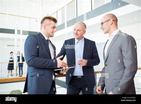 Male Professional Explaining Project To Colleagues On Digital Tablet In
