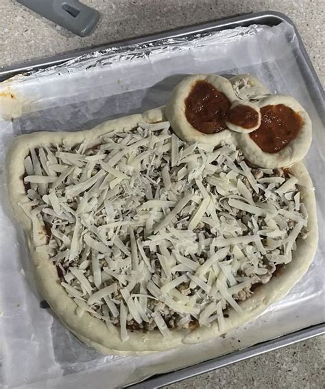An Uncooked Pizza Sitting On Top Of A Pan Covered In Cheese And Sauce