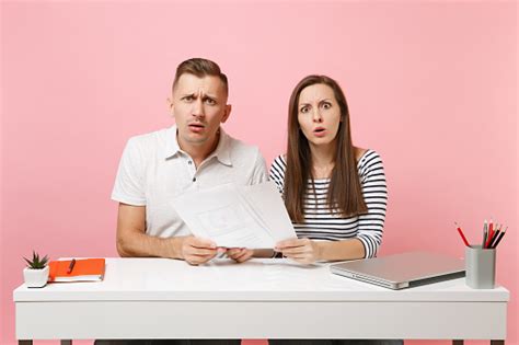 두 젊은 피로 비즈니스 여자 남자 동료 파스텔 핑크 배경에 고립 된 현대 노트북 작업 흰색 책상에서 앉아 성과 경력 개념입니다