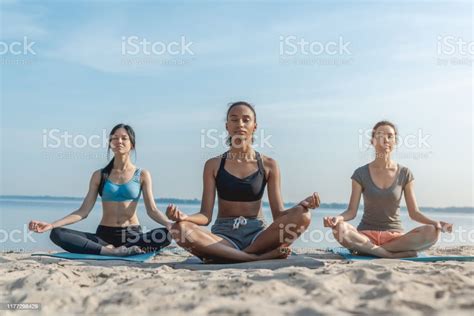 바다 해변에서 연꽃 위치에 명상 스포티 한 여자의 전면보기 요가 컨셉 3 명에 대한 스톡 사진 및 기타 이미지 3 명 강사 개념 Istock