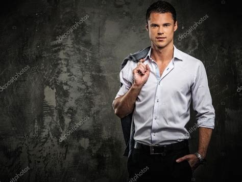 Скачать Красивый мужчина в рубашке гранж стену держа пиджак через плечо — стоковое