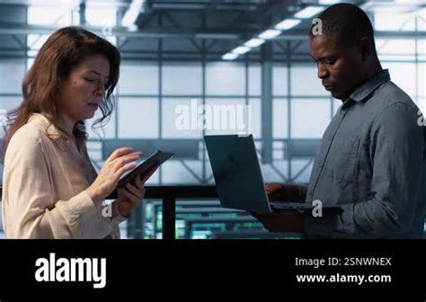 Portrait Of Happy System Administrators In Data Center Using Devices Verifying Firewall