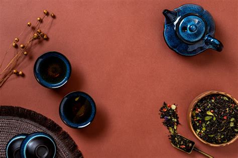 갈색 배경에 블루 주전자 차 한 잔과 차 잎 뜨거운 허브 차는 테이블의 주전자에 있습니다 공간을 복사합니다 0명에 대한 스톡