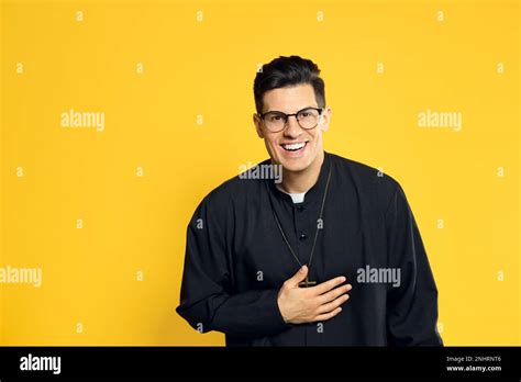 Priest In Cassock With Clerical Collar Laughing On Yellow Background