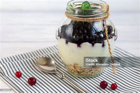 세라믹 숟가락으로 나무 빛 배경에 유리 항아리에 건포도와 오트밀건강한 파르페 민트로 장식되어 있습니다 건강한 다이어트 음식 채식