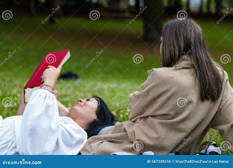 Chica Tendida En Las Piernas De Su Amigo Mientras Lee Un Libro Sobre La