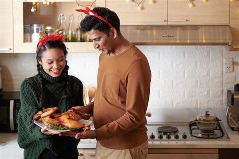 Emocionado joven mirando el pollo frito que su esposa cocinó para la cena de navidad Foto Premium