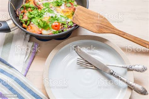 신선한 소박한 아침 식사계란 베이컨 양파와 냄비에 체리 토마토와 흰색 나무 테이블에 나이프와 포크 빈 접시 0명에 대한 스톡