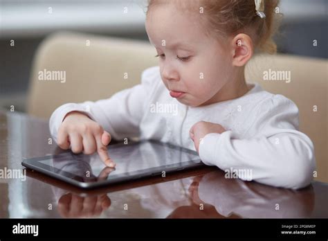 A Little Surprised Girl Is Playing With A Digital Wireless Tablet