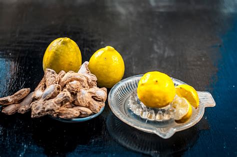 원시 신선한 익은 레몬 또는 밀 감속 Limon 아유르베다 허브와 어두운 고딕 색상에서 검은색 나무 표면에 유리 압착 기에 건조