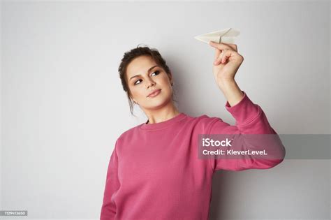 분홍색 Hoody 젊은 아름 다운 여자 손을 모델 종이 공기 비행기 들고 빈 회색 배경에 공기 비행기 여행 컨셉의 디자인 개념에