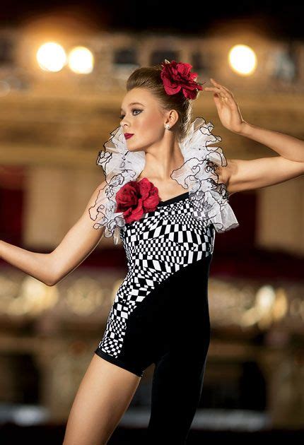 A Woman In A Black And White Dress With Red Flowers On Her Head Is Dancing