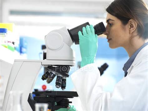 Scientist Examining Specimen Under Microscope During Clinical Trial In