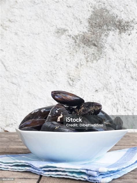 신선 하 고 원시 바다 면 파란색과 녹색 냅킨에 흰색 세라믹 그릇에 홍합 나무 테이블과 흰색 벽 배경입니다 사이드 뷰입니다 0