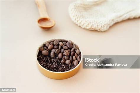 커피 스크럽 큰 과립과 커피 콩 골드 항아리 나무 숟가락에 화장품 오일과 파스텔 베이지 배경에 대한 거친 마사지 장갑 수제 스킨 케어 선택적 초점 각질제거에 대한 스톡 사진