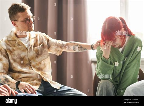 Young Man With Tattoos Comforts Young Woman Who Is Visibly Upset
