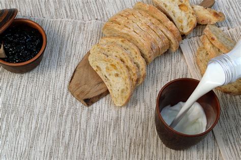 맛있는 아침 식사 잼과 우유를 곁들인 신선한 빵 우유를 컵에 붓습니다 냅킨에 과일 잼토스트 균형 잡힌 음식 소박한 스타일 빵과