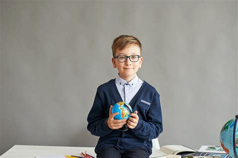 학교로 돌아 가기 안경을 쓴 재미있는 작은 남학생이 과제를 수행합니다 학용품을 가진 초등학생부터 아이 교육 및 학교 개념 원격