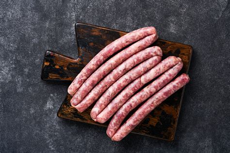 생 소시지 Bratwurst 또는 복사 공간이있는 돌 배경에 향신료가있는 커팅 보드에 재료가있는 소시지 음식 요리 배경 상단