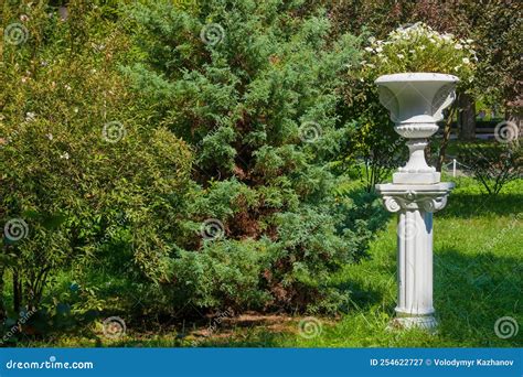 Large White Ceramic Vase With Flowers On A Column In The Garden On A