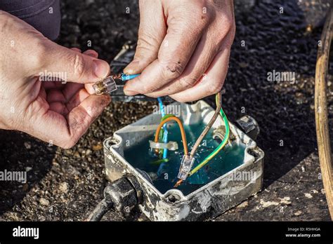 Hands Of Electrician With Terminal Forbox And Screwdriver Tighten Up Switching Electric Actuator
