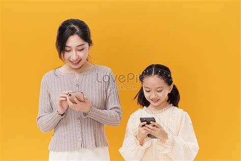 아래를 내려다 보면서 휴대 전화를 가지고 노는 엄마와 딸 듀오 사진 무료 다운로드 Lovepik