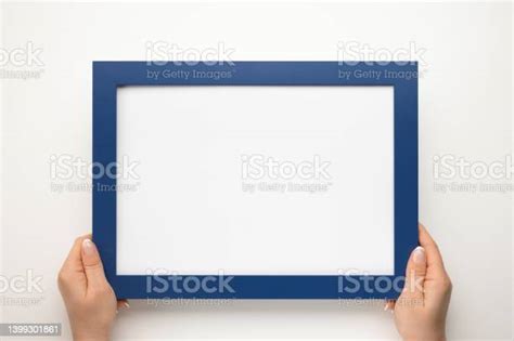 프레임 모형을 잡기 사진 모형 여자 손은 파란색 프레임을 잡고 있습니다 프레임과 포스터 디자인용 프레임 크기 A4 손에 복사 공간이 있는 빈 사진 프레임 테두리가 닫힙니다