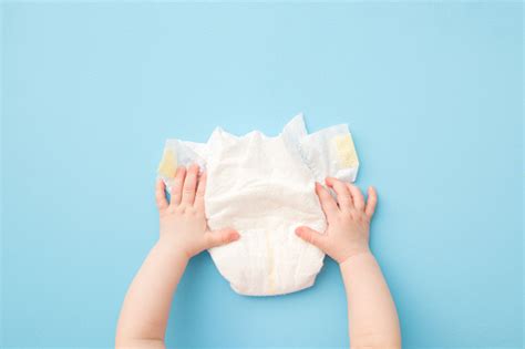 밝은 파란색 테이블 배경에 흰색 기저귀를 만지는 아기 손입니다 파스텔 색상입니다 근접 촬영 시점 샷 하향하 보기 기저귀