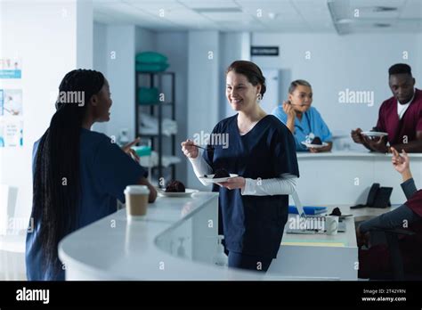Happy Diverse Male And Female Doctors Eating Birthday Cake At Reception