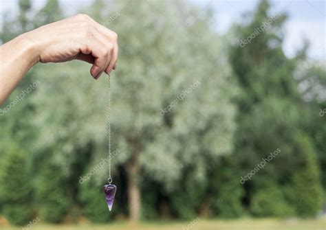 Mujer De La Mano Sosteniendo Y Utilizando Péndulo De Cristal De Cuarzo