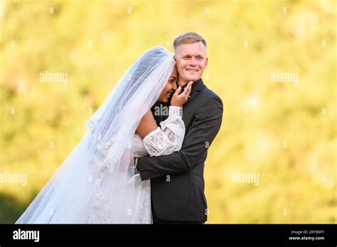 Happy Newlyweds Against The Backdrop Of Sunny Evening Foliage The Girl Laughs And Buries
